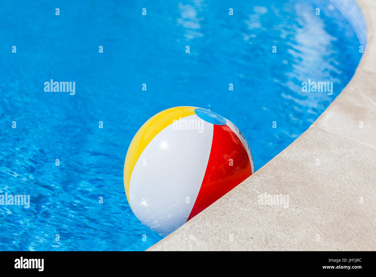 Inflatable beach ball floating in an outdoor swimming pool Stock Photo ...