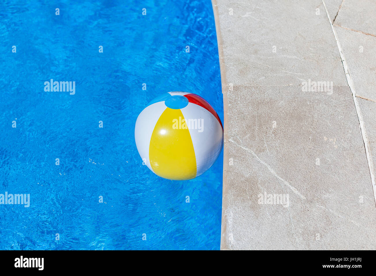 Inflatable beach ball floating in an outdoor swimming pool Stock Photo ...