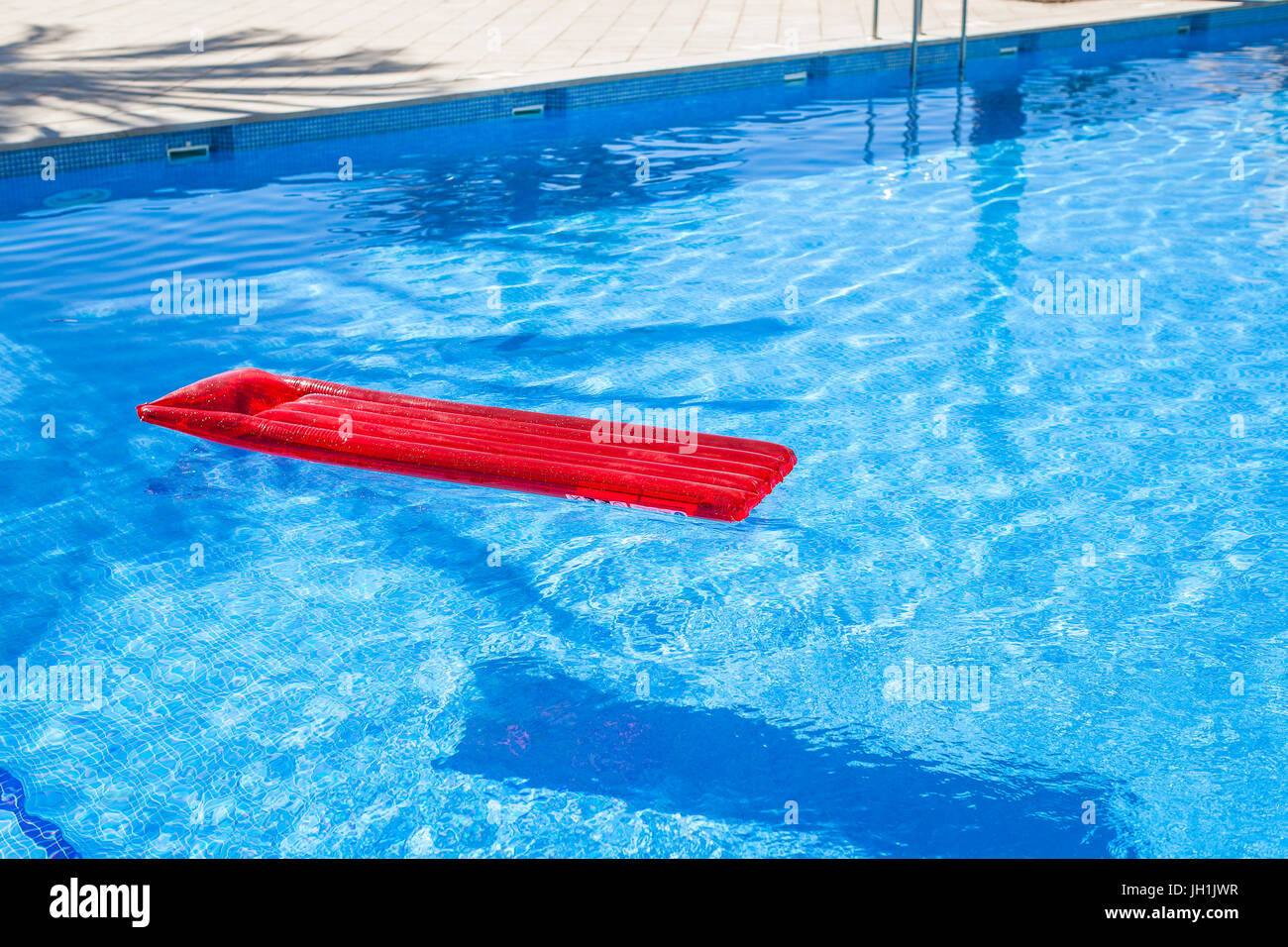 Red inflatable lilo lounger floating in a swimming pool Stock Photo - Alamy
