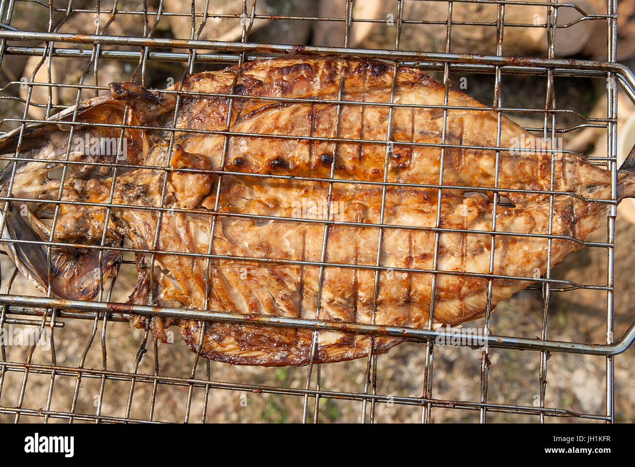 Fresh fish with sauce cooked on an open flame grill. Roasted fish with ...
