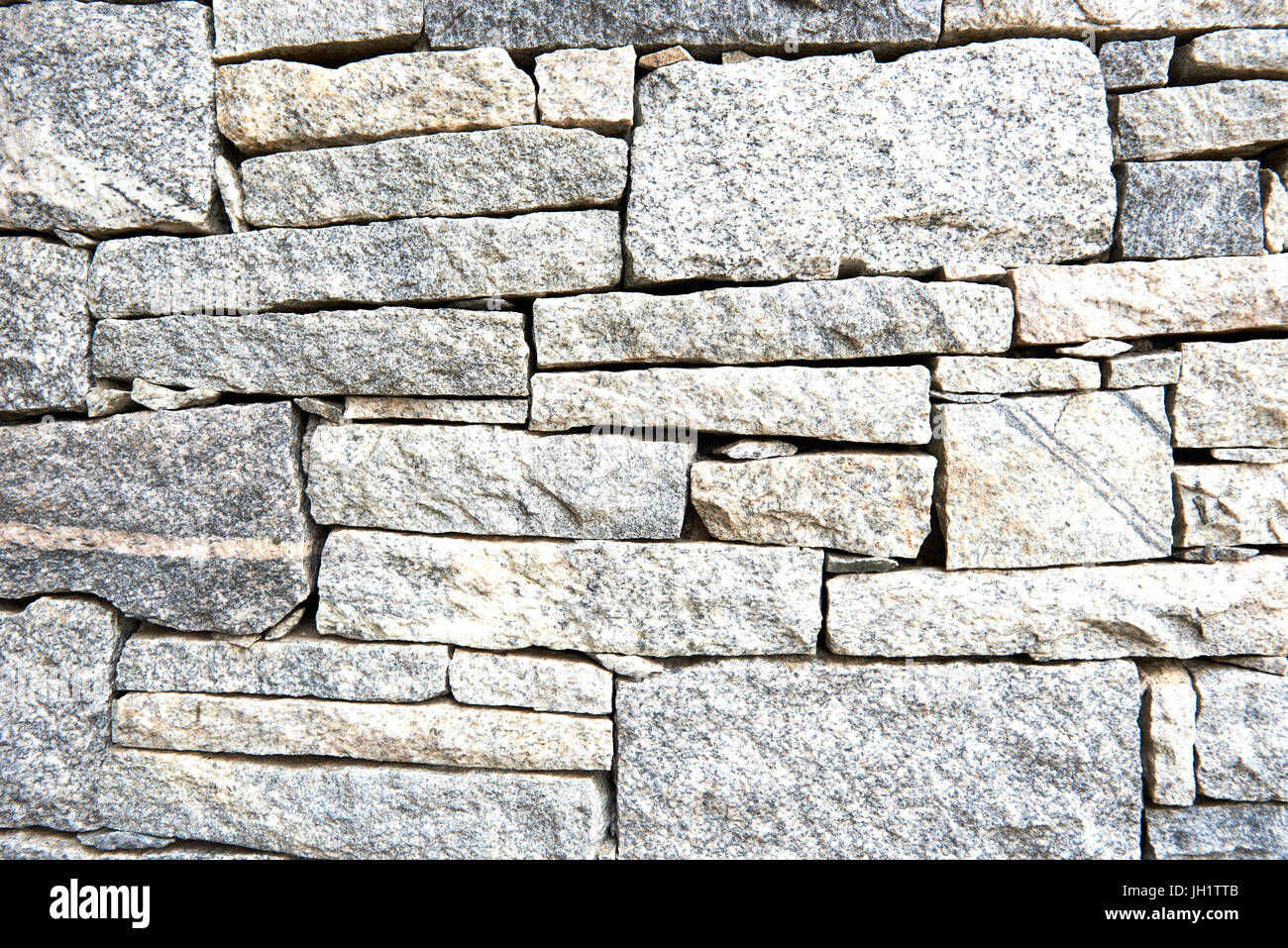 Textured geometric pattern of a granite stone wall Stock Photo - Alamy