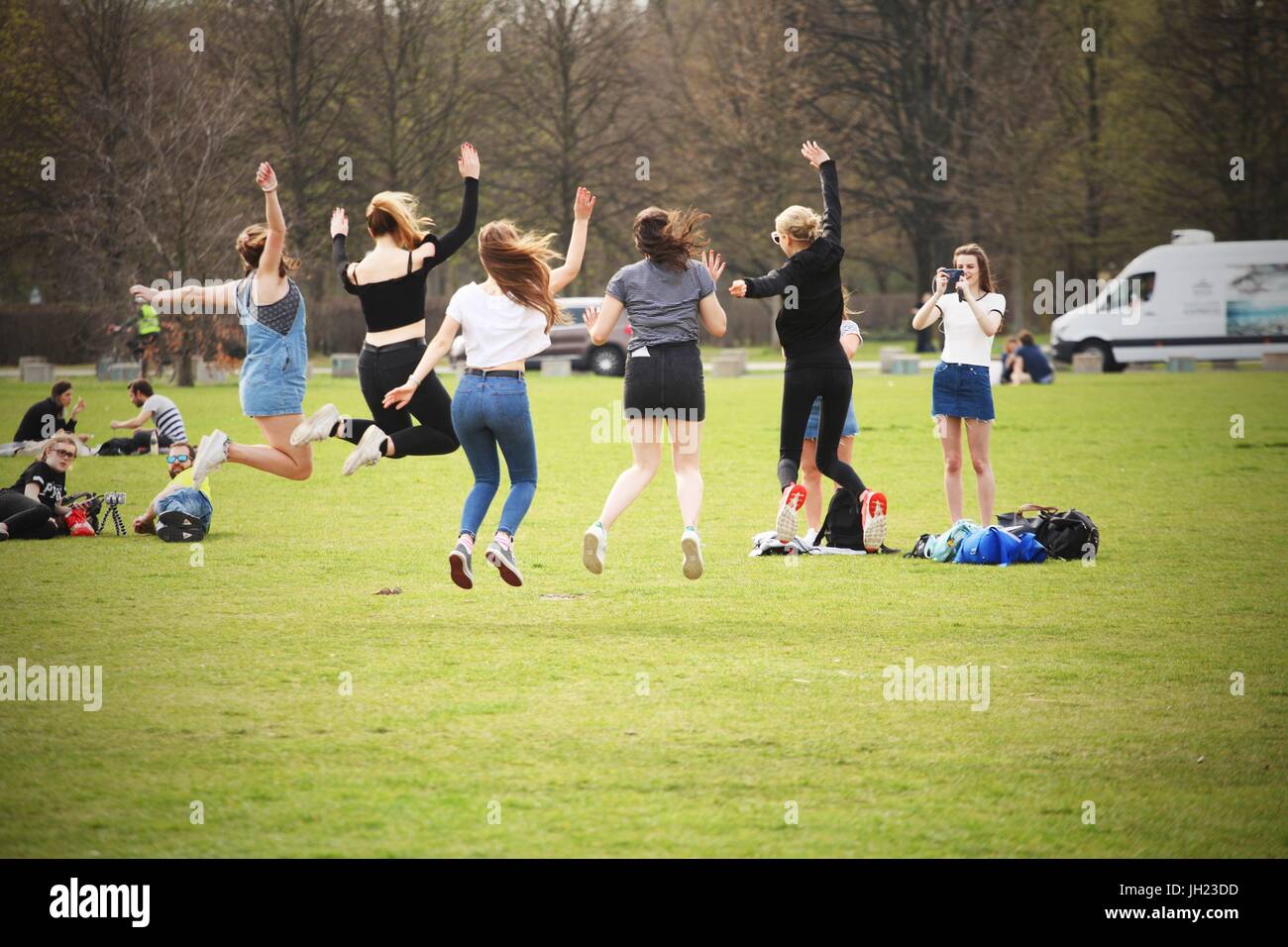Young female German tourists jump up for a group photo on a lane in ...