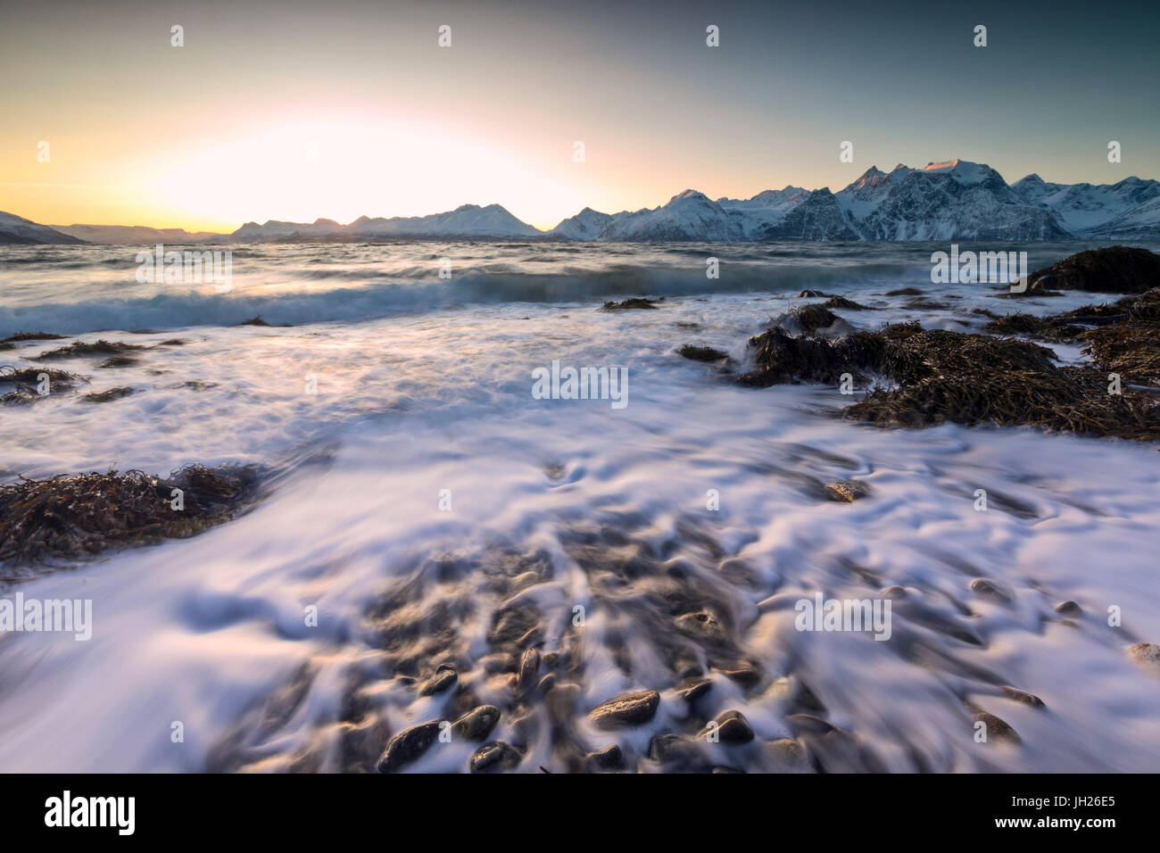 The sunset light reflected on the waves of cold sea crashing on the ...