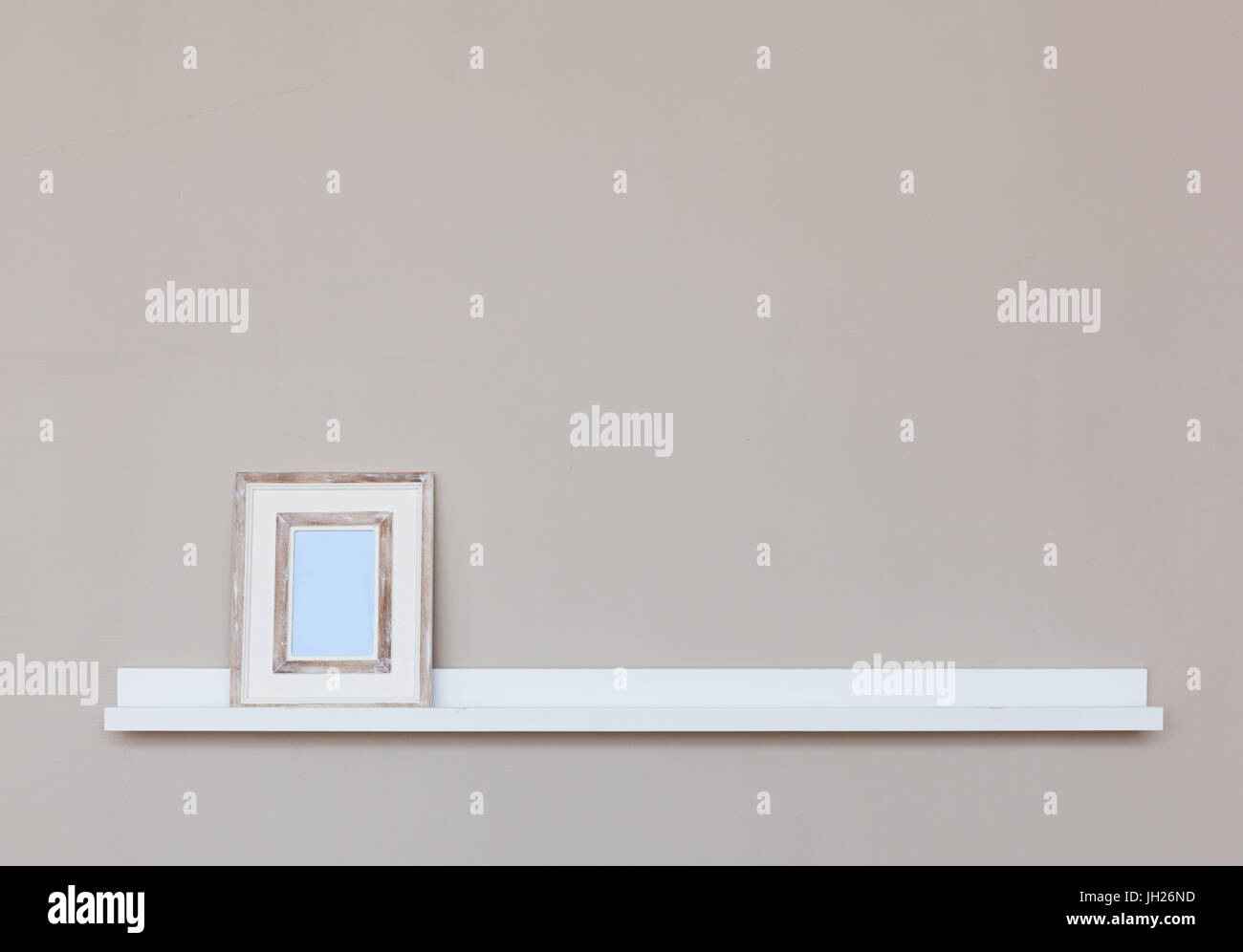 Close up of small white shelf with picture frame on wall Stock Photo ...