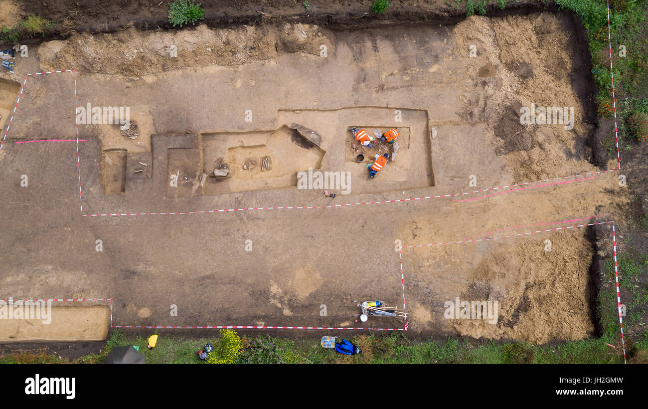 Excavation helpers work on graves at an archaeological excavation site ...