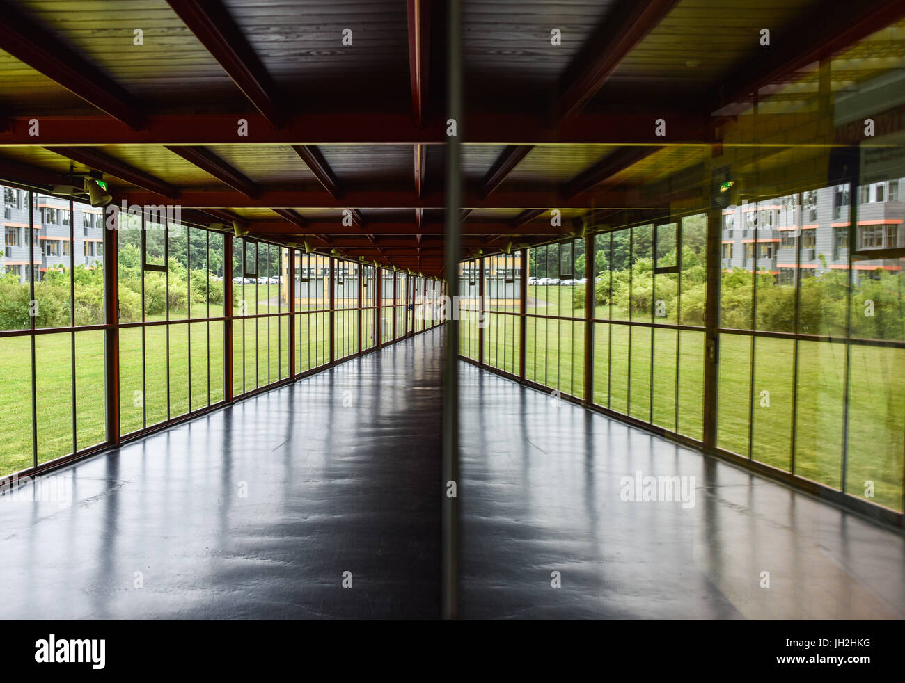 A long glass corridor, which is reflected in a glass panel of a door ...