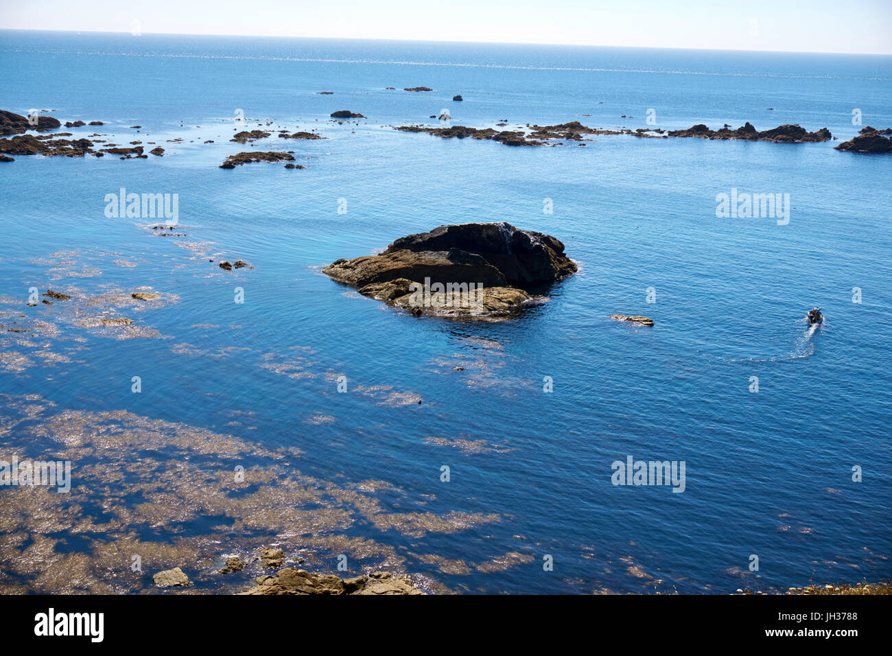 Sea and rocks with motor boat (and possibly a basking seal), near ...