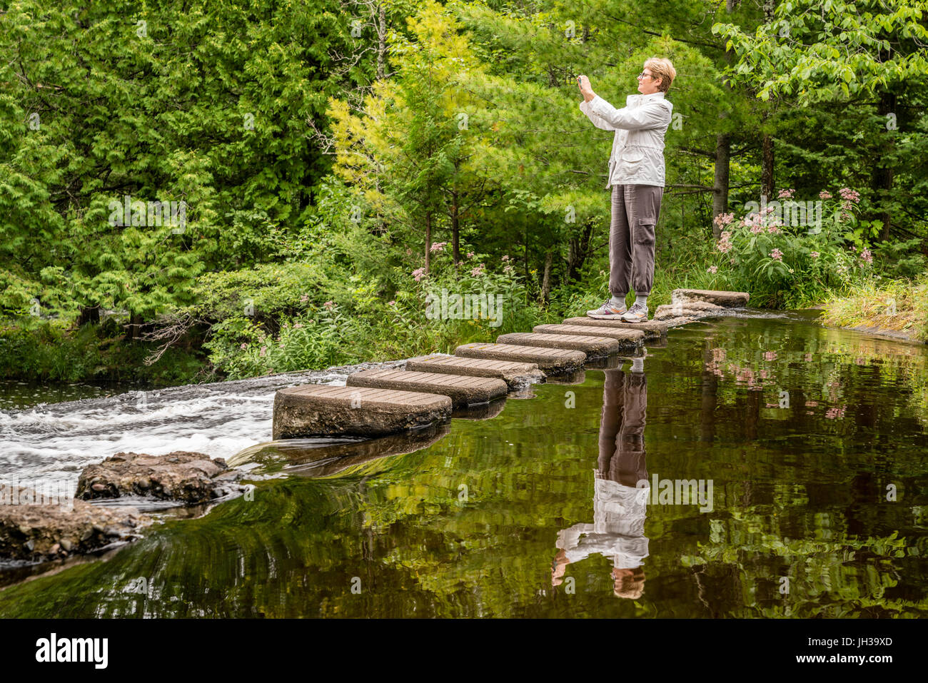 Woman is taking photographs of a stream in Michigan's Upper Peninsula ...