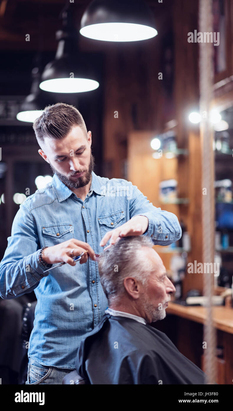 Handsome good looking barber cutting hair Stock Photo - Alamy