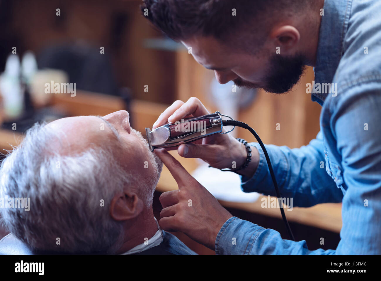Pleasant hard working barber holding an electric shaver Stock Photo - Alamy