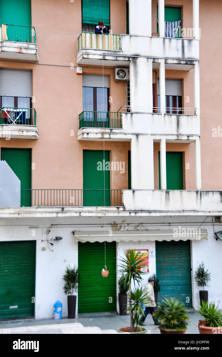 A woman hoisting up a basket of shopping up to her fourth floor ...