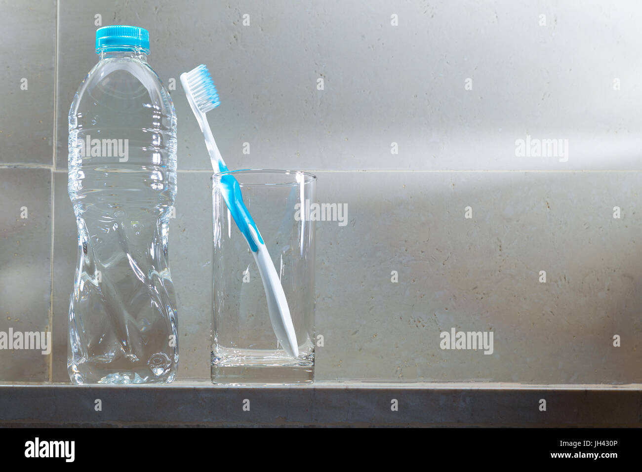 white toothbrush in clear glass cup and full bottle of drinking water ...