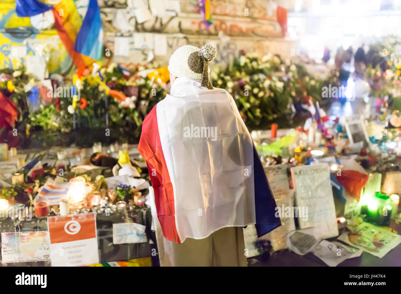 A man holding a french flag in front of la republique. Spontaneous ...