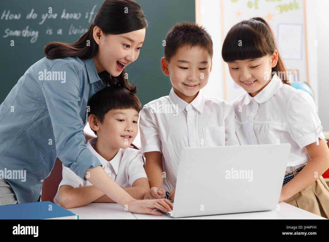 Female teacher helping students studying in classroom Stock Photo - Alamy