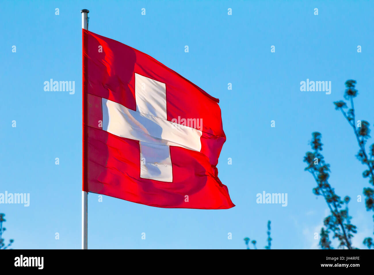 Swiss Confederation, Switzerland national flag waving on blue sky ...