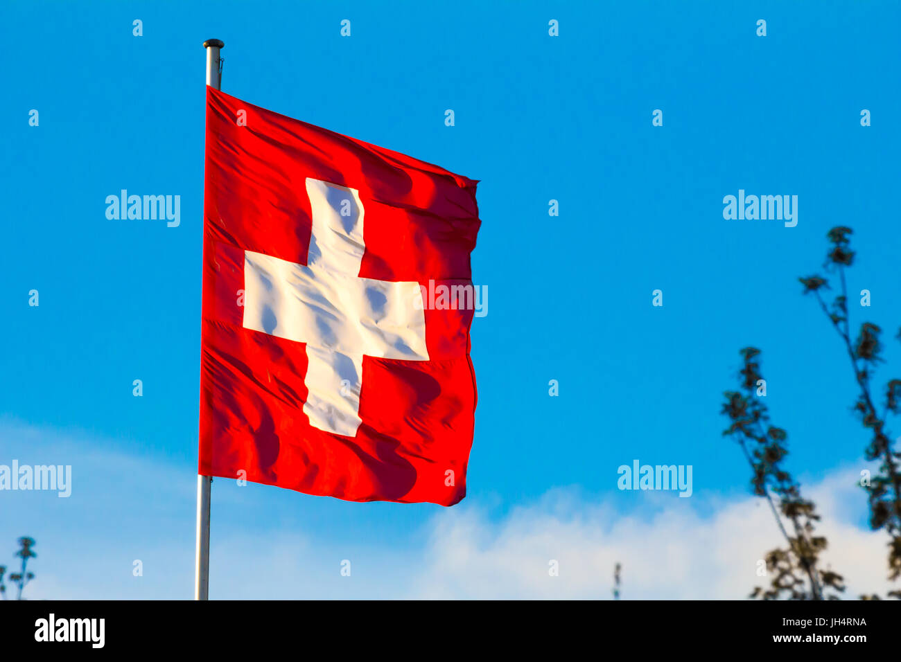 Swiss Confederation, Switzerland national flag waving on blue sky ...