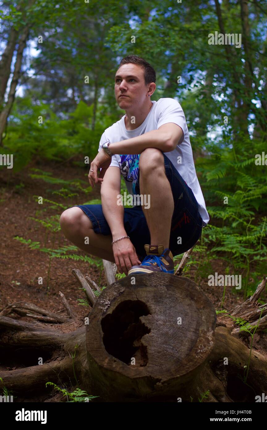 Man crouched on tree stump, Rushmere Stock Photo - Alamy