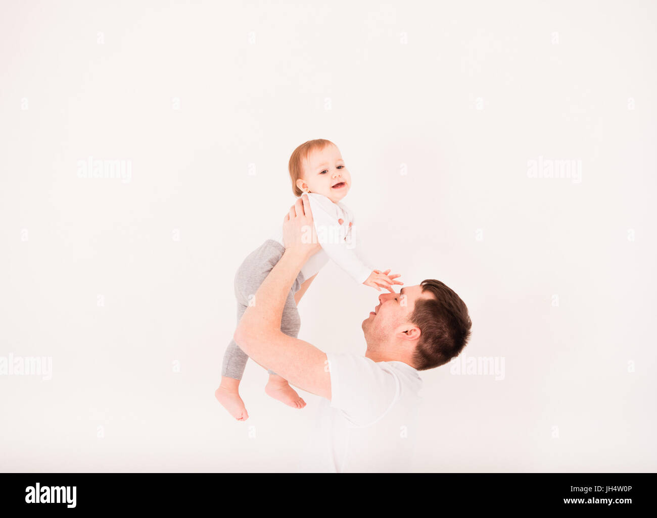 Young father lifts up his little baby girl, isolated on white Stock ...