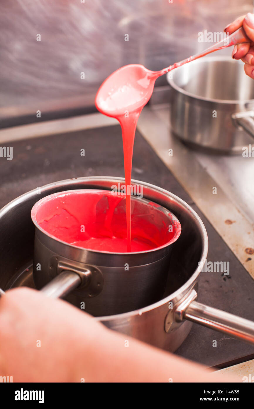 Cooking mirror glaze, red liquid in the pan Stock Photo - Alamy