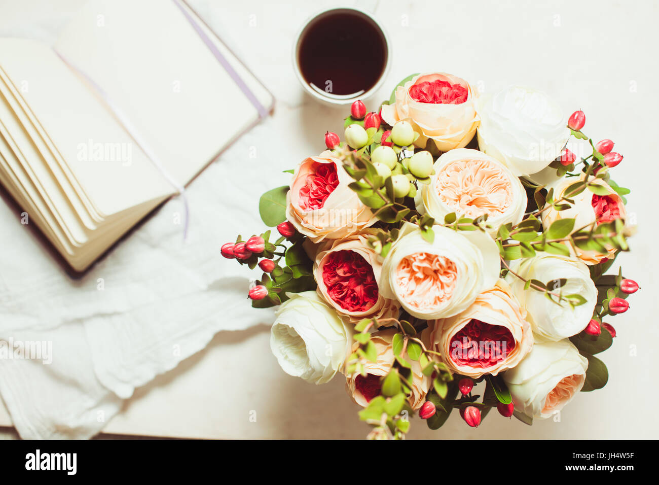 A cup of black tea, notebook and beautiful flowers on the table, top ...