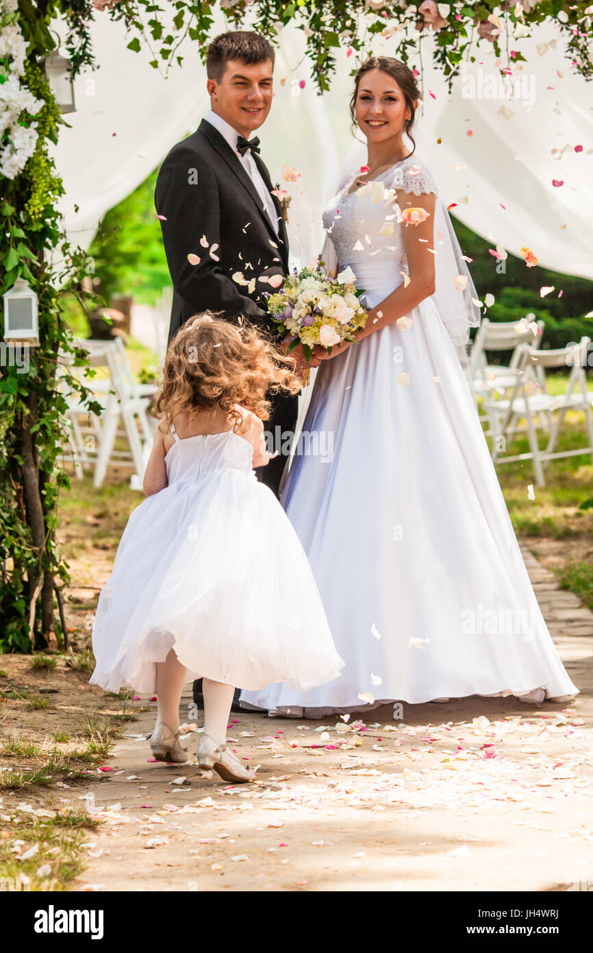 Bride and groom on the wedding ceremony. Adorable girl showered the ...