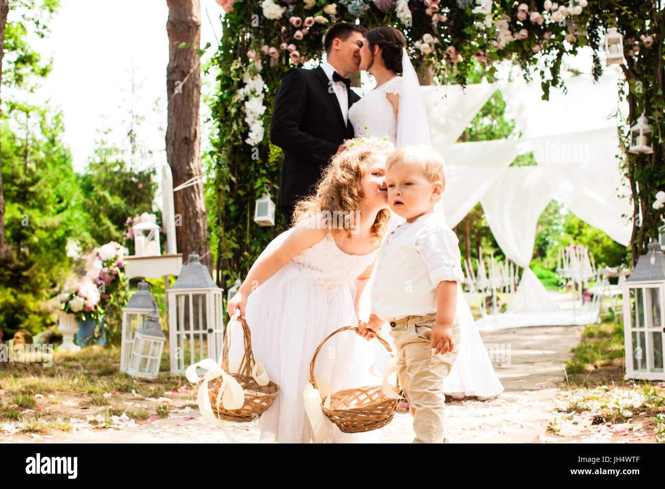 Bride and groom are kissing after wedding ceremony. Adorable children ...