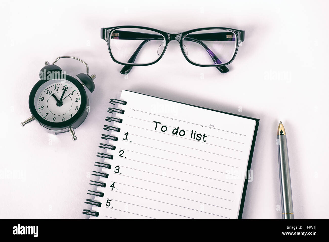 To do list written on a notepad with eyeglasses, pen and alarm clock ...