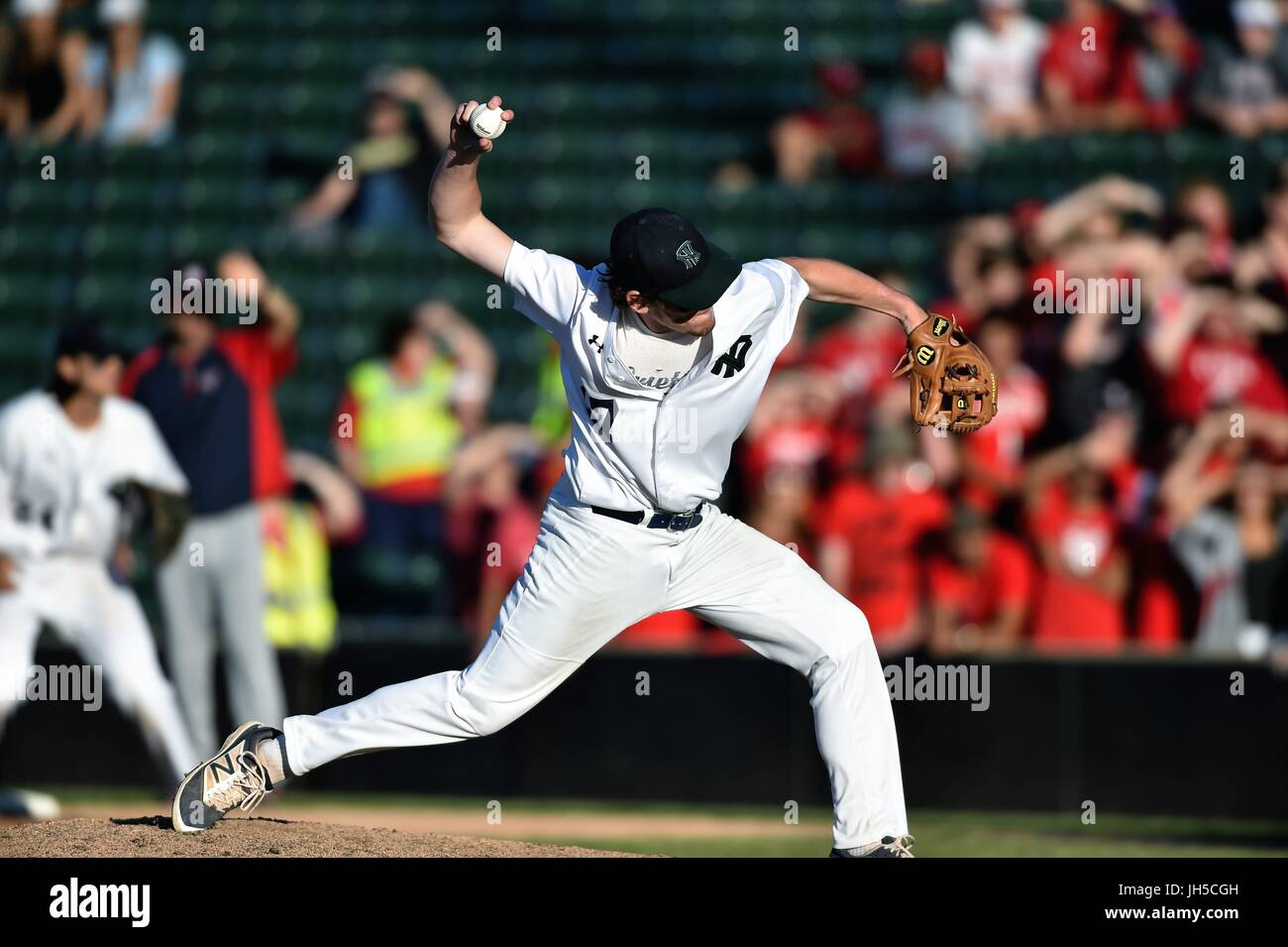 Pitcher delivering a pitch to an opposing hitter during a high school ...