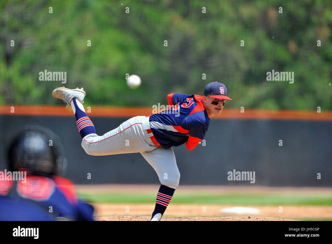 Pitcher delivering a pitch to an opposing hitter during a high school ...