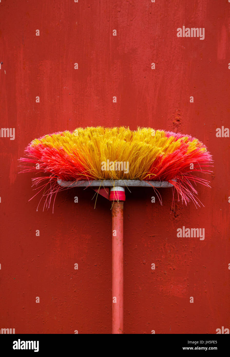 Old red broom with metal hand grip against red wall Stock Photo - Alamy
