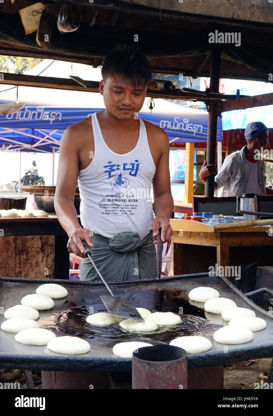 Mandalay, Myanmar - Feb 21, 2016. A Burmese man cooking cakes at market ...