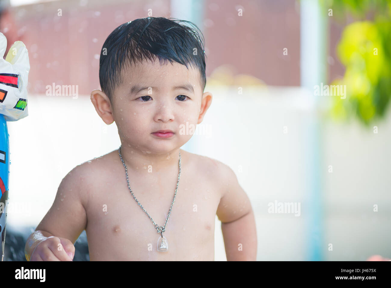 Sad Asian kid playing alone in inflatable baby pool. Boy swim and ...