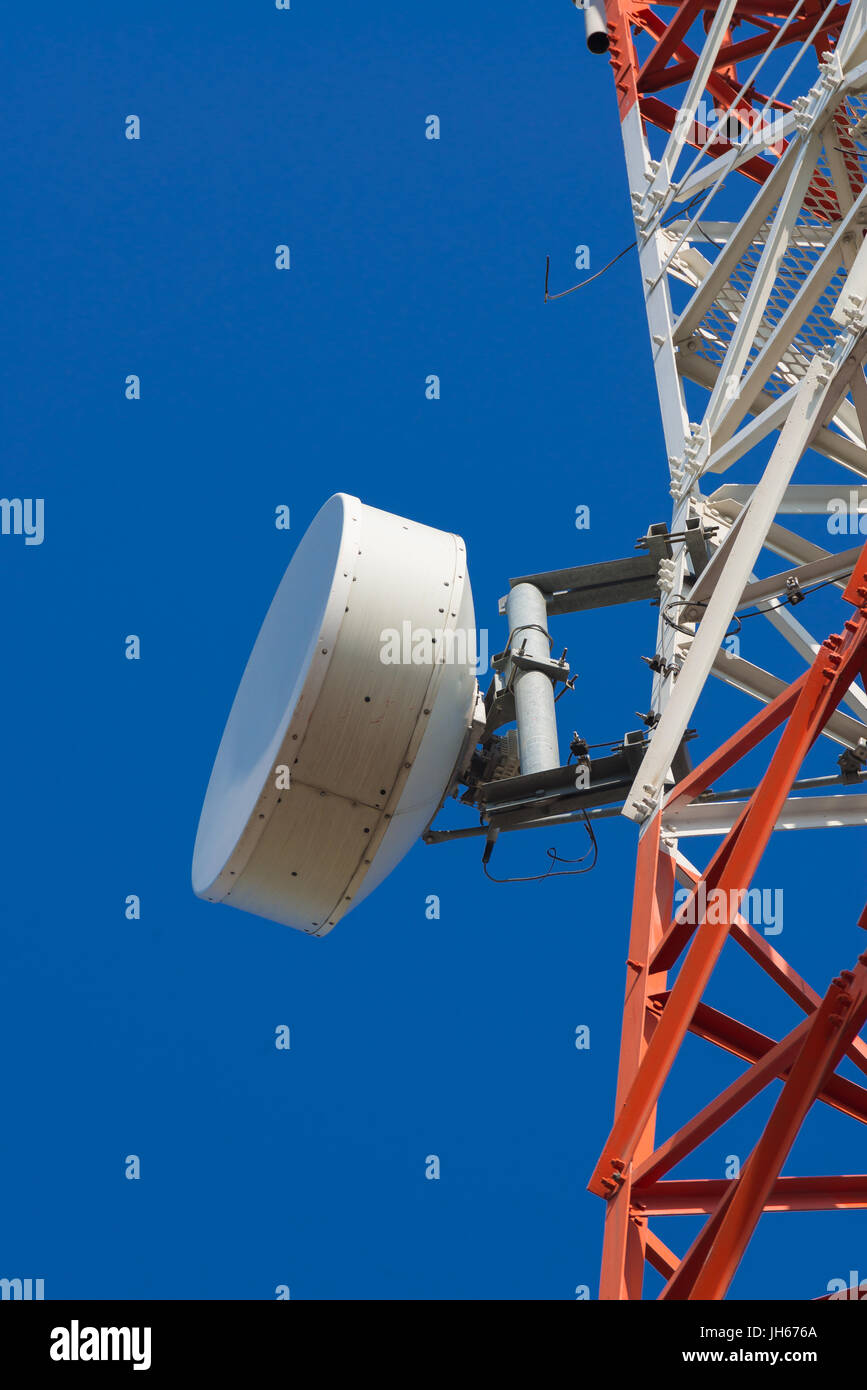 Mobile phone communication antenna tower with satellite dish on blue ...