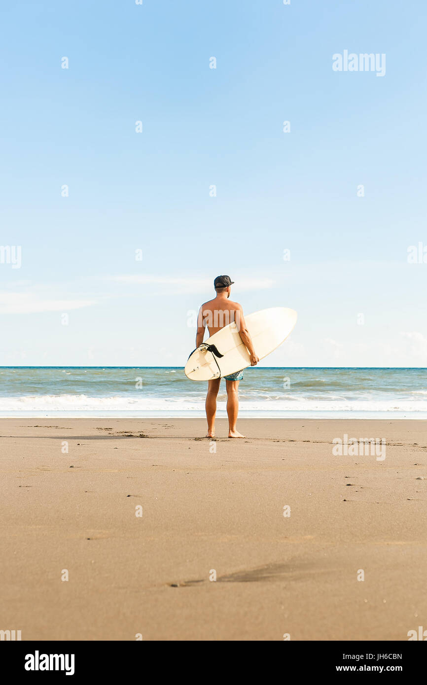 Handsome man stand with long surf surfing board wait on surf spot at ...