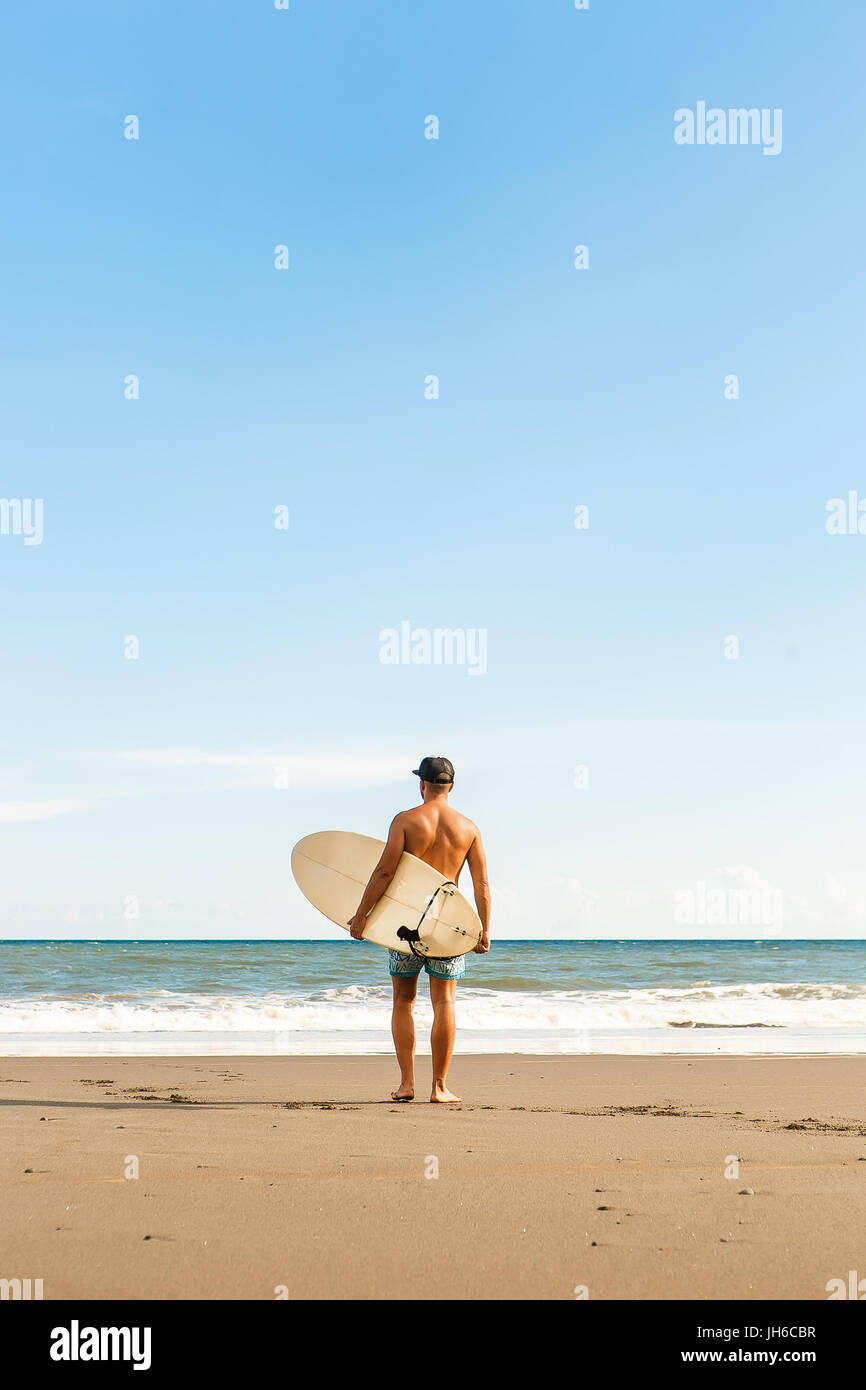 Handsome fit man stand with long surf surfing board wait for wave on ...