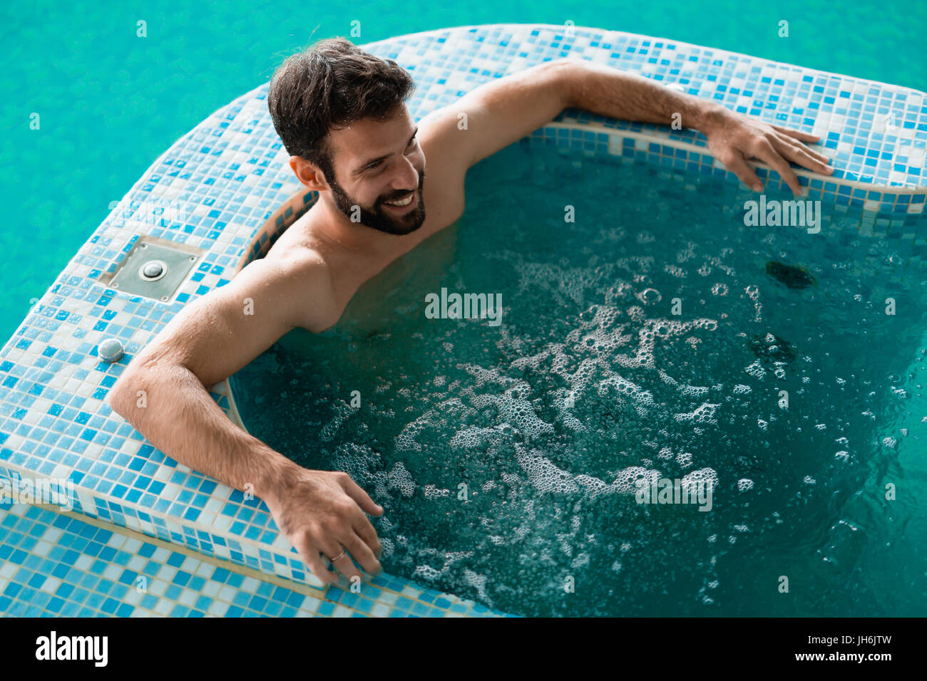 Attractive man enjoying spending time in jacuzzi Stock Photo - Alamy