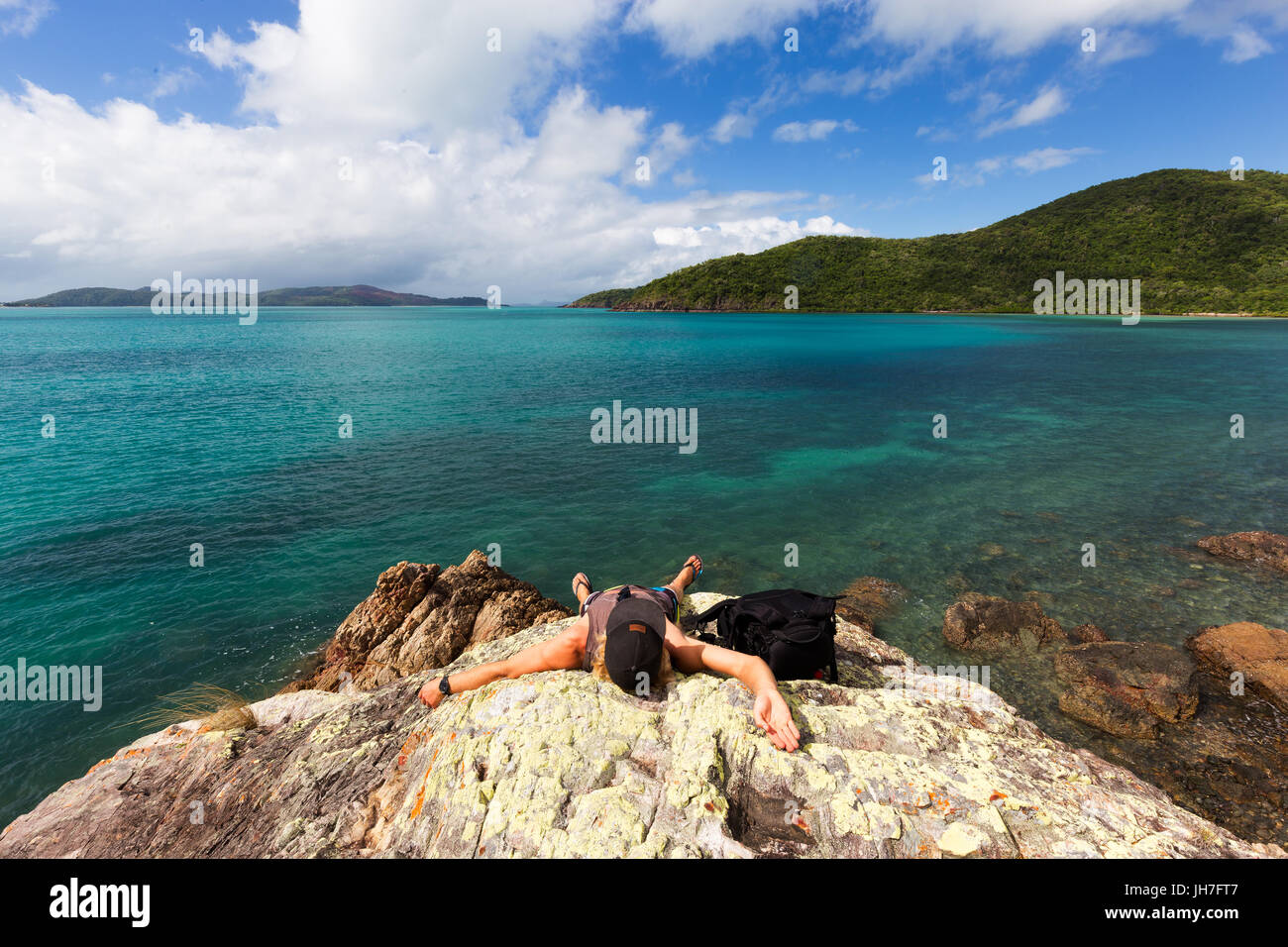 An exhausted traveler rests on a boulder at a beautiful isolated ...