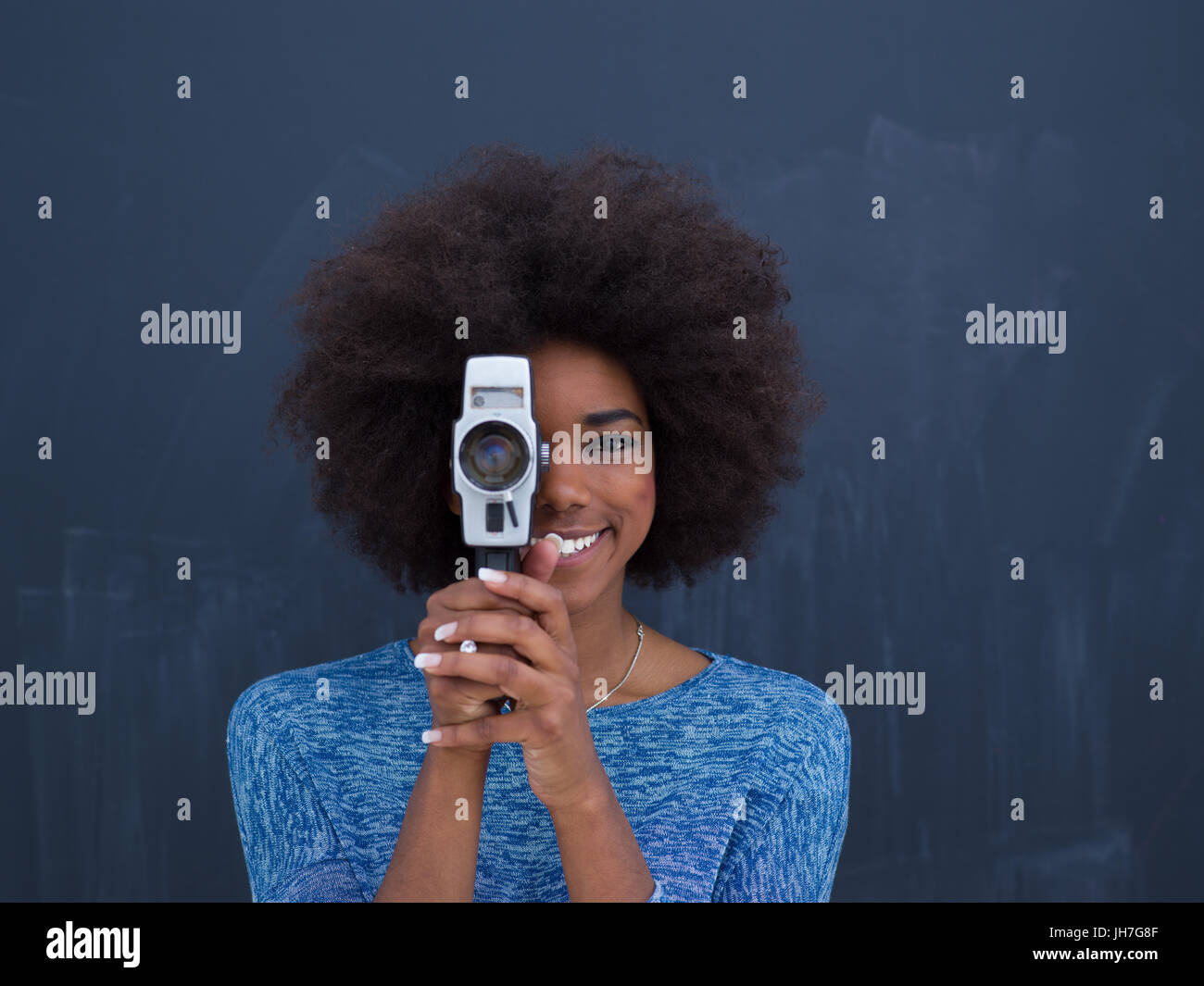 A young beautiful african american woman using a retro video camera ...