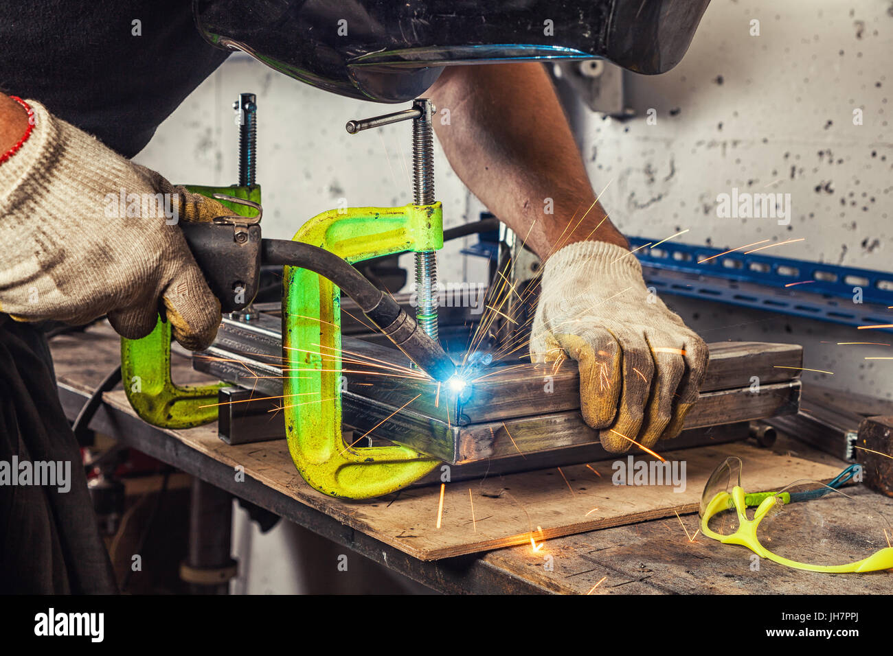 Close-up A strong man welder in a black T-shirt, welds a metal welding ...