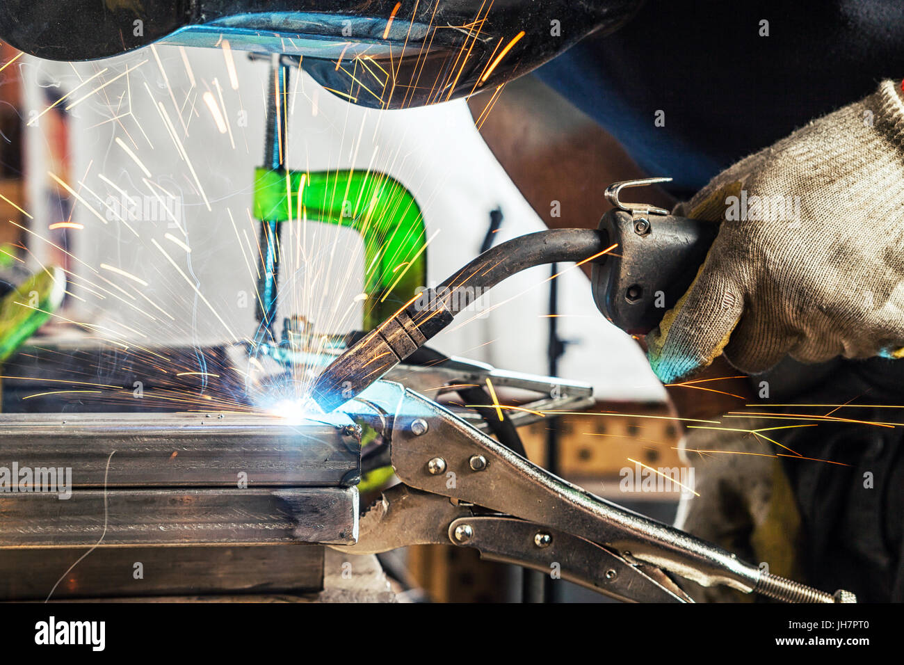 A close-up of a strong male welder in a black T-shirt, welds a metal ...