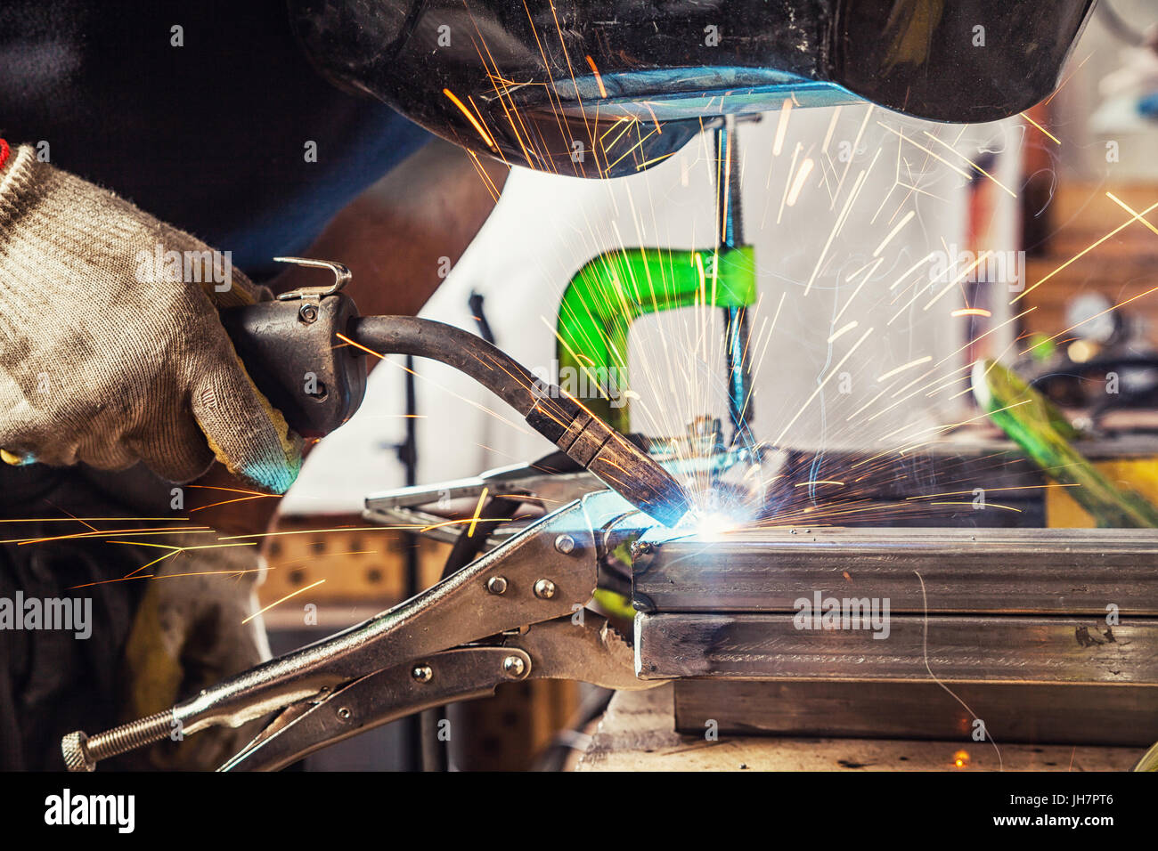 A close-up of a strong male welder in a black T-shirt, welds a metal ...