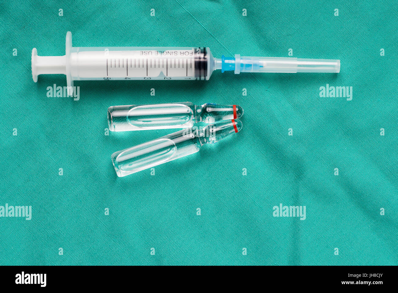 Medical syringe and vials lying on the hospital's green background. The ...