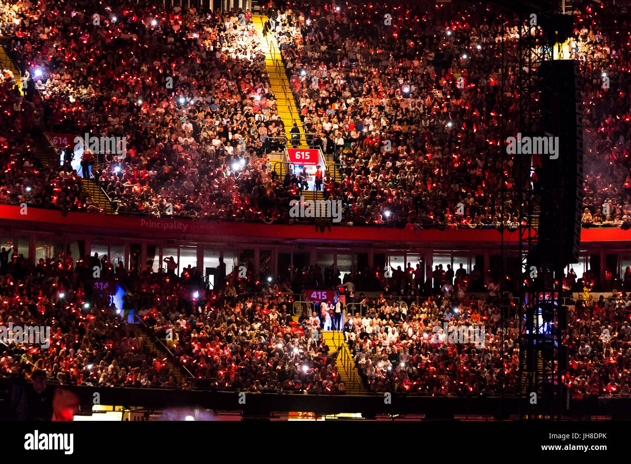 Fans in the crowd illuminated by their light-up wristbands watch ...