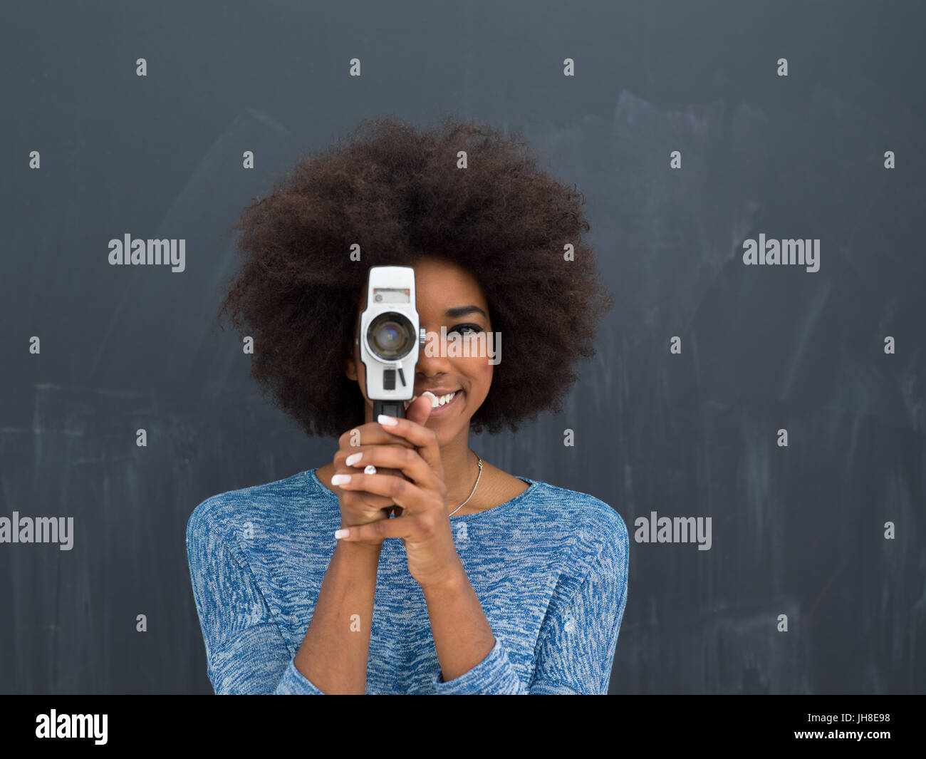 A young beautiful african american woman using a retro video camera ...