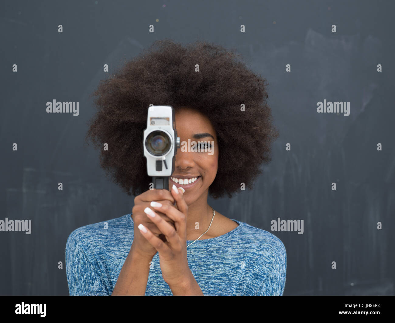 A young beautiful african american woman using a retro video camera ...