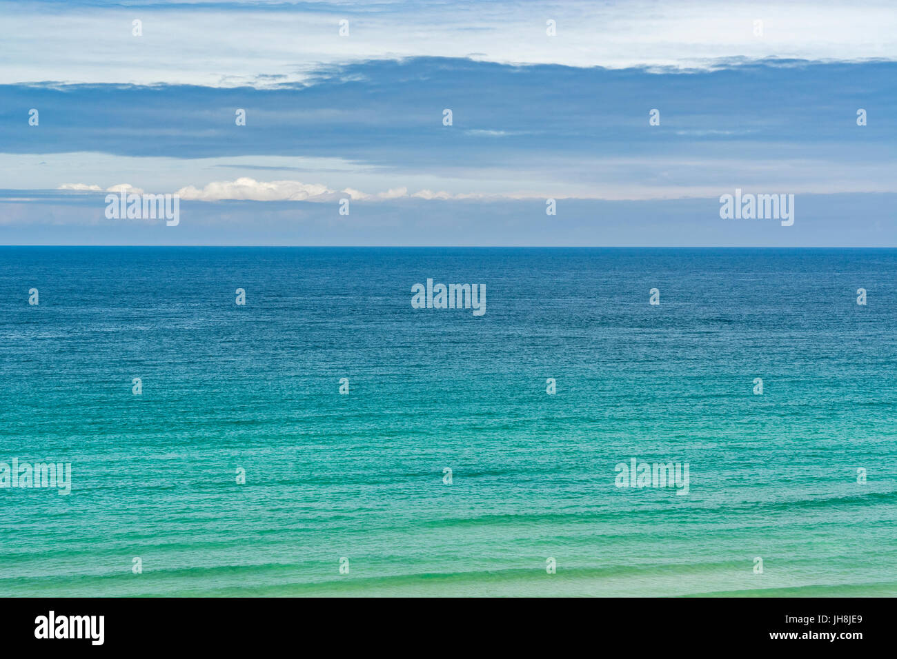 Summer time calm blue sea and sky off Fistral Beach at the tourist town ...