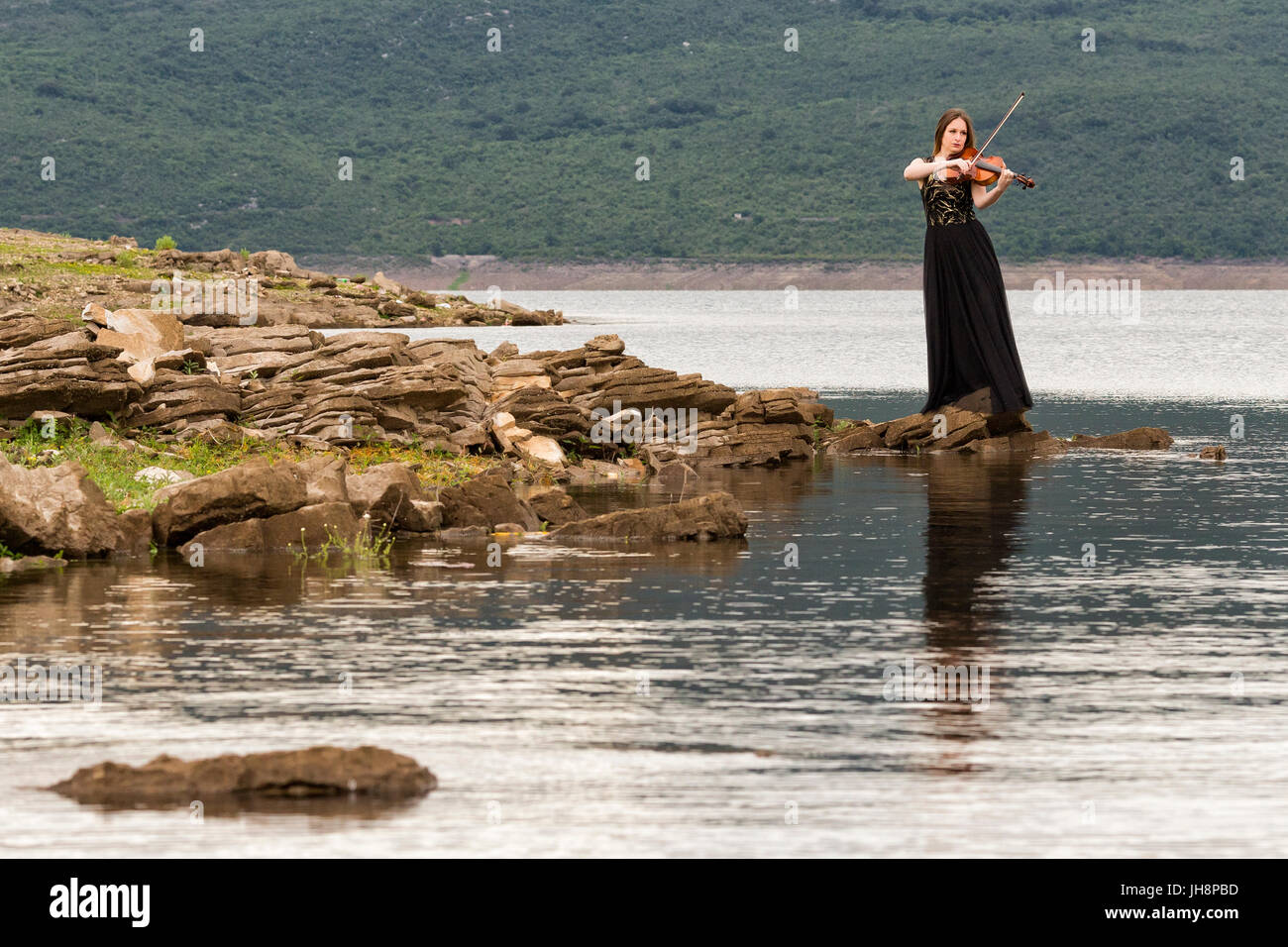 Beautiful female viola player on the lake shore Stock Photo - Alamy
