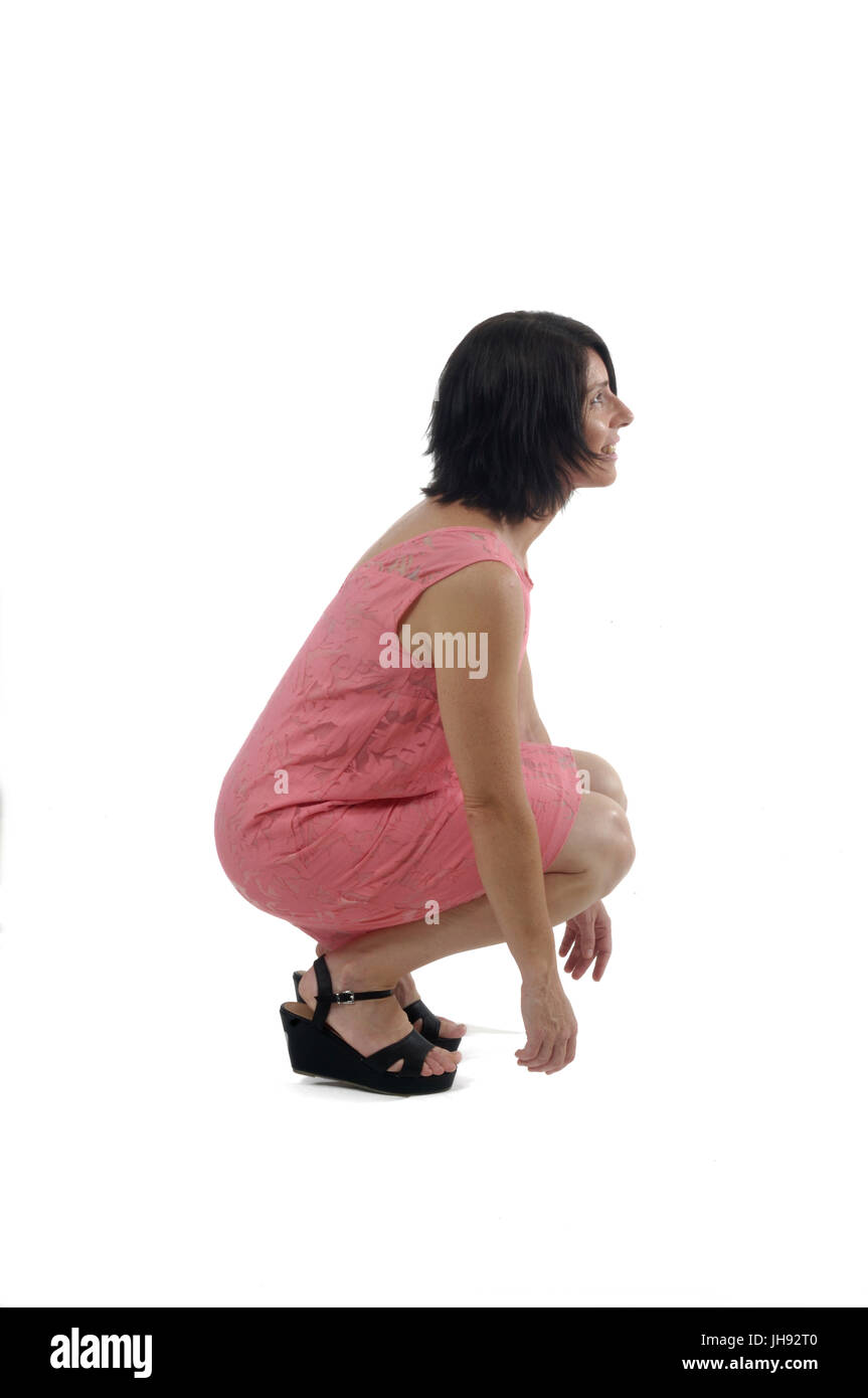 Woman with a dress crouching on a white background Stock Photo - Alamy