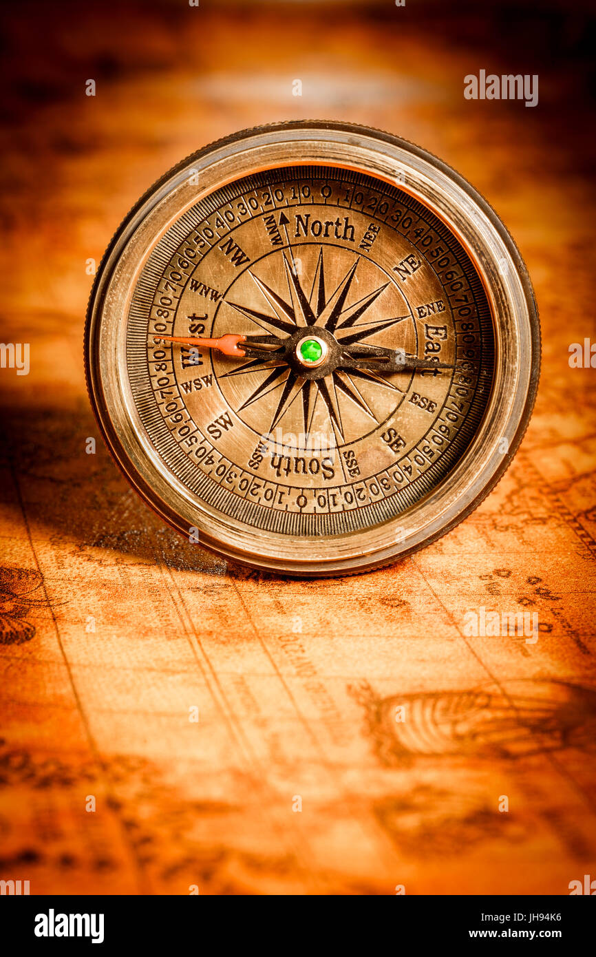 Vintage still life. Vintage compass lies on an ancient world map in ...