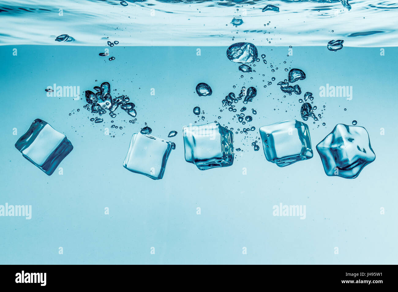 Ice cubes falling into the water sinking to the bottom. Abstract ...